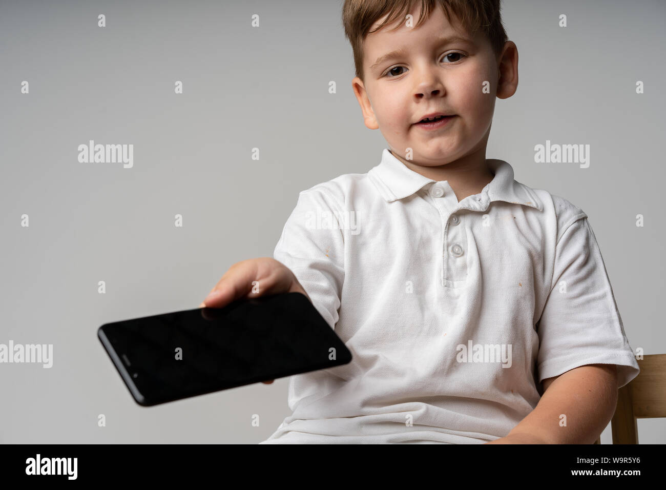 Younger poor boy got a new smartphone and looks happy. Social network ...