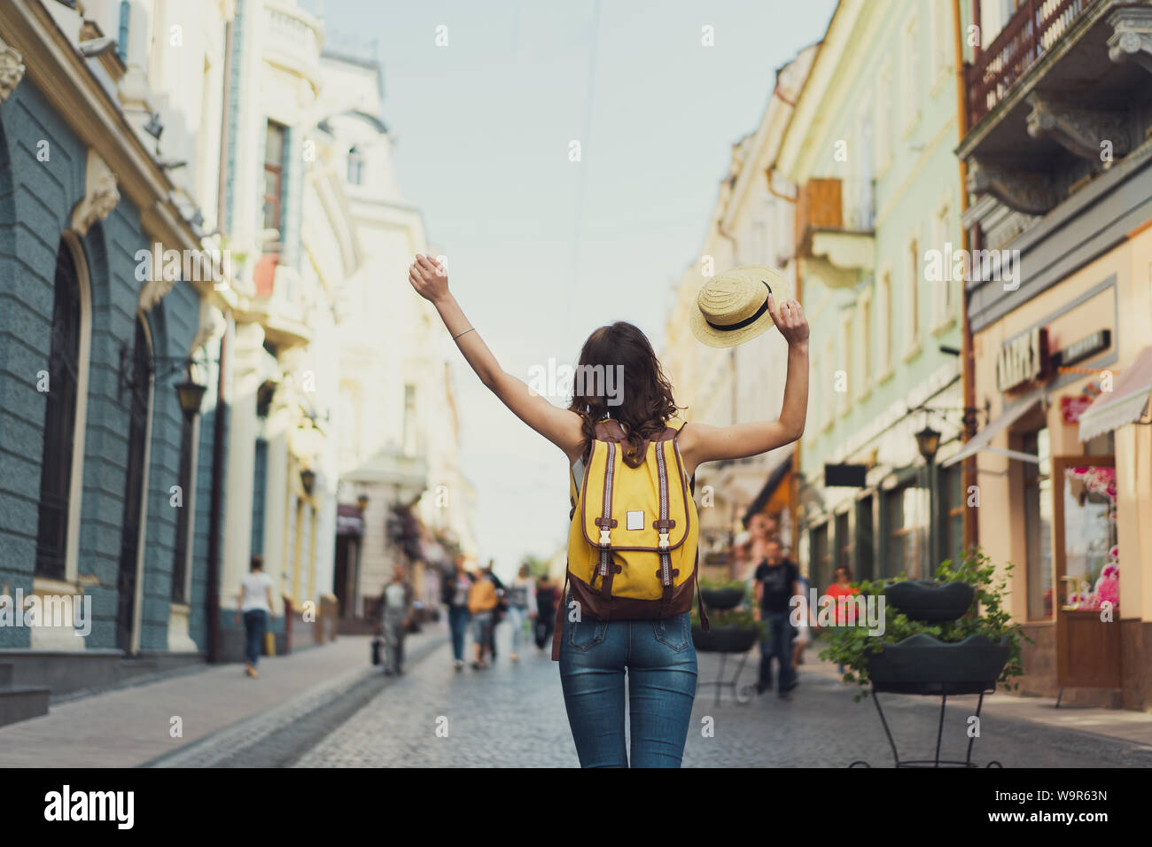 Back view of a young woman traveler with a backpack on her shoulder out ...