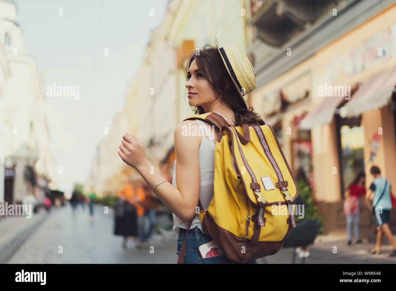 Back view of a young woman traveler with a backpack on her shoulder out ...