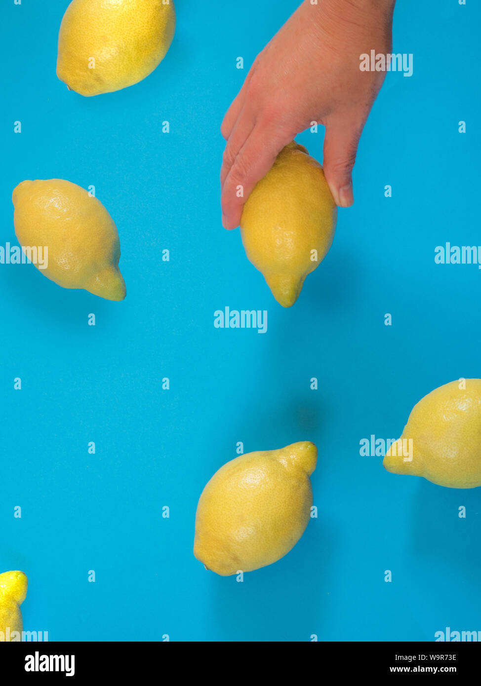 Hand holding a lemon on blue background Stock Photo - Alamy