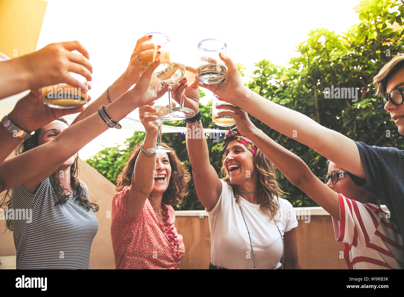 Group of happy friends cheering with glasses at dinner outdoor in ...