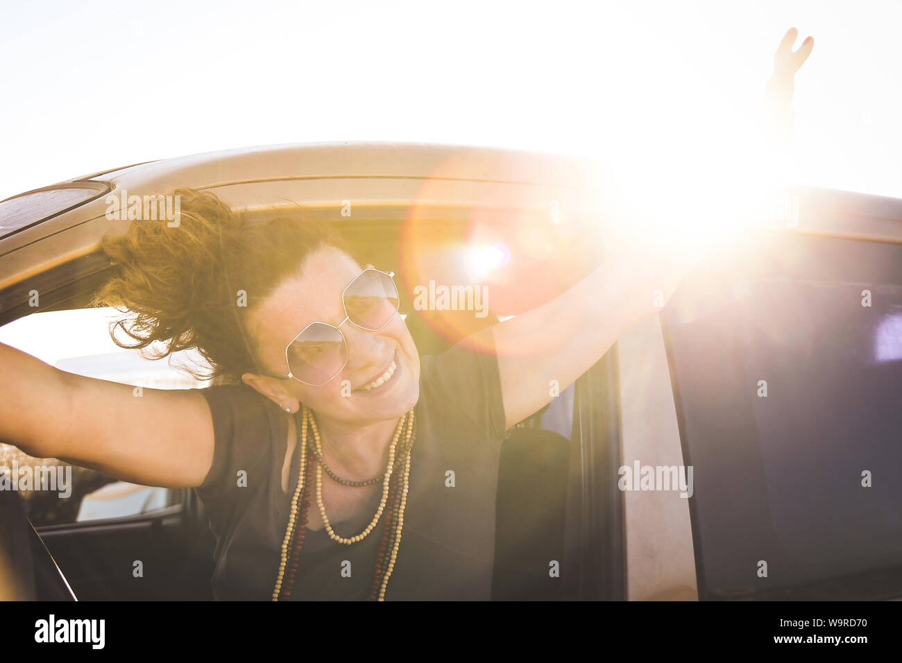 Woman enjoying a beautiful vacation sunny day sitting in a car with ...