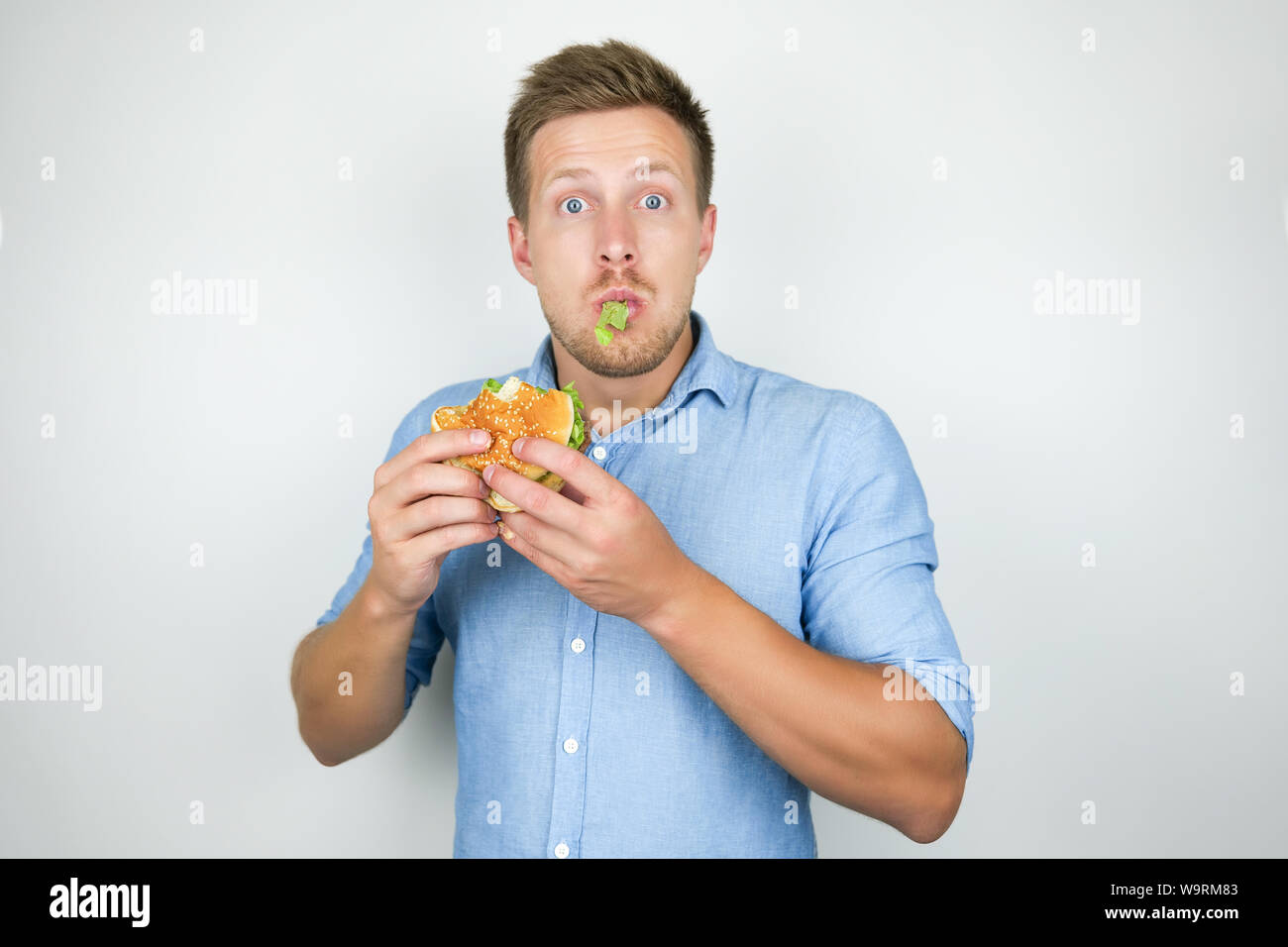 young handsome man biting cheeseburger from fast food restaurant ...