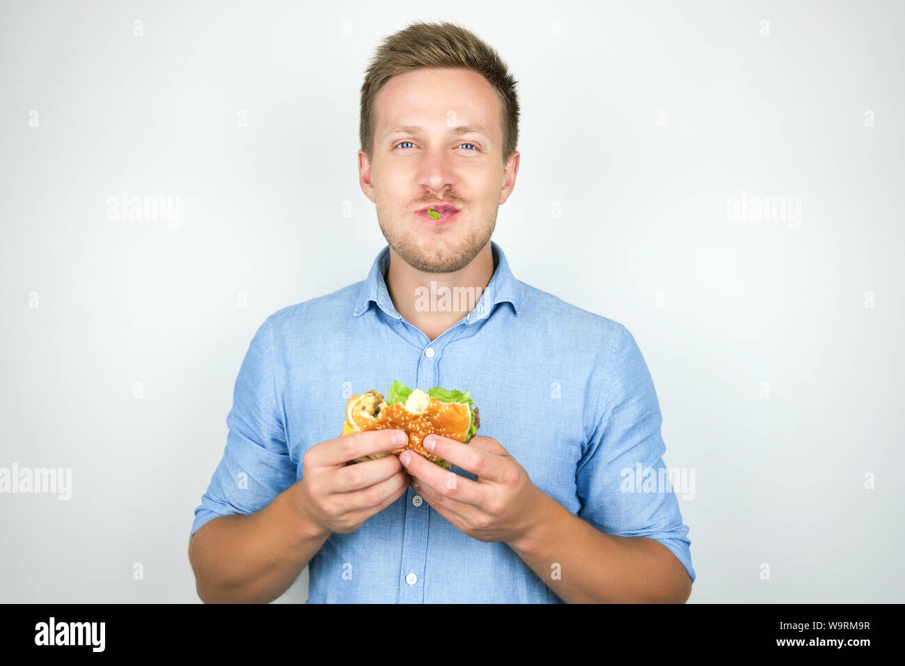 young smiling man biting cheeseburger from fast food restaurant ...