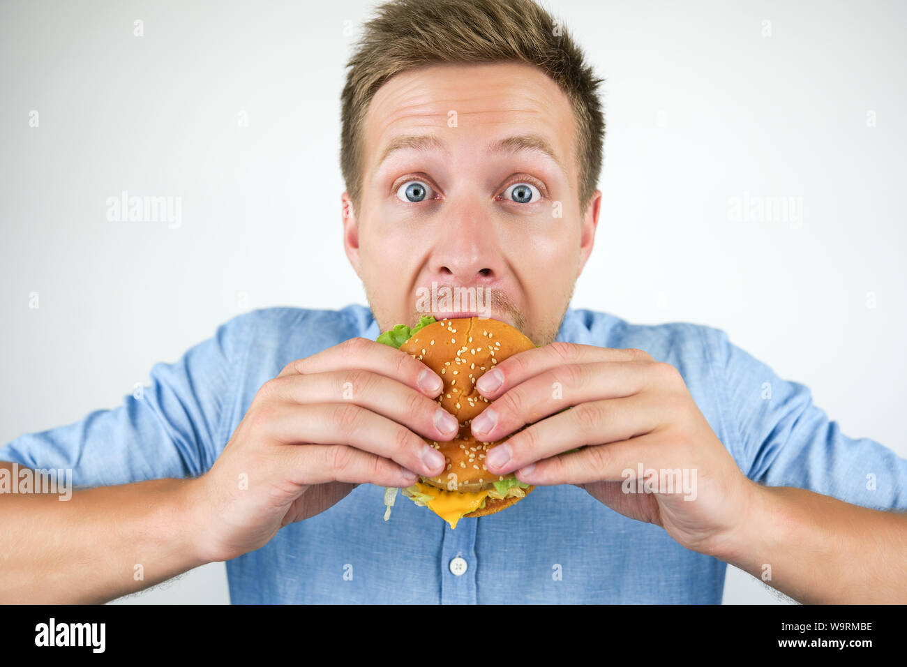 young handsome man biting cheeseburger from fast food restaurant ...