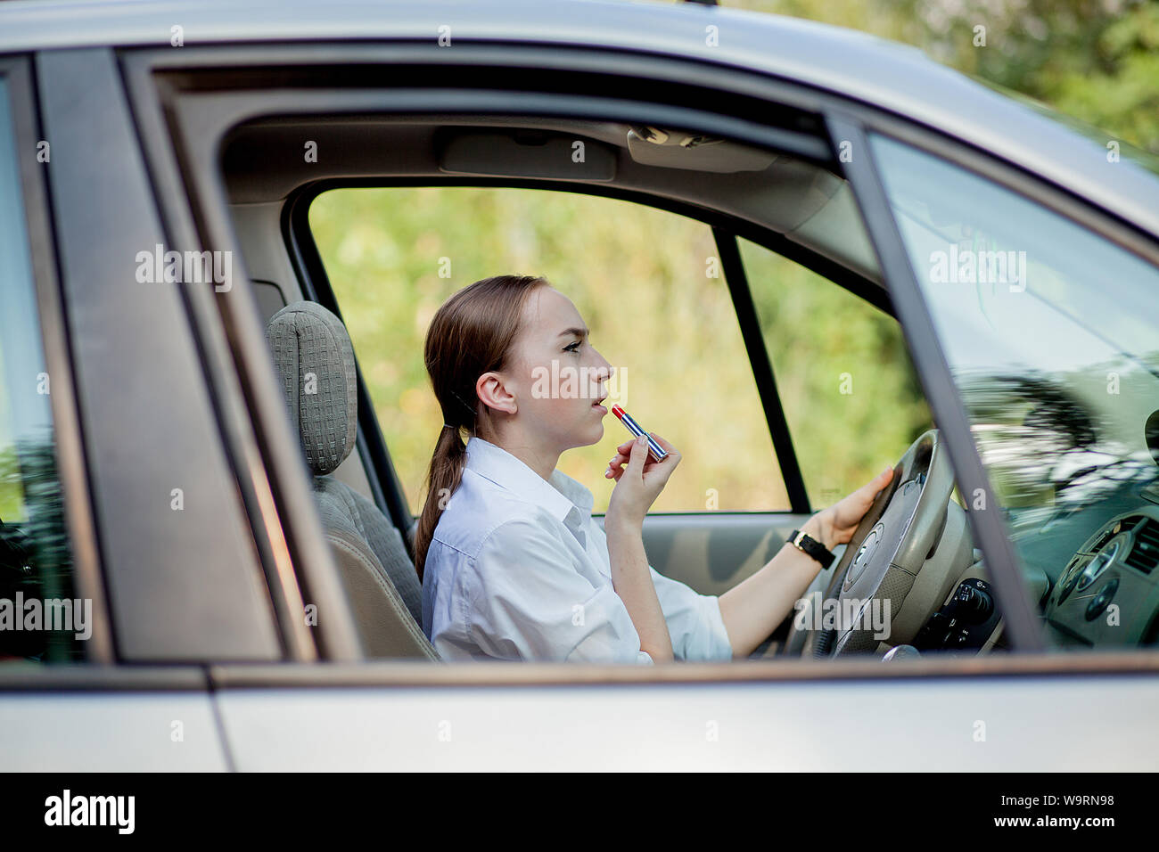 Young woman driving applying makeup hi-res stock photography and images ...