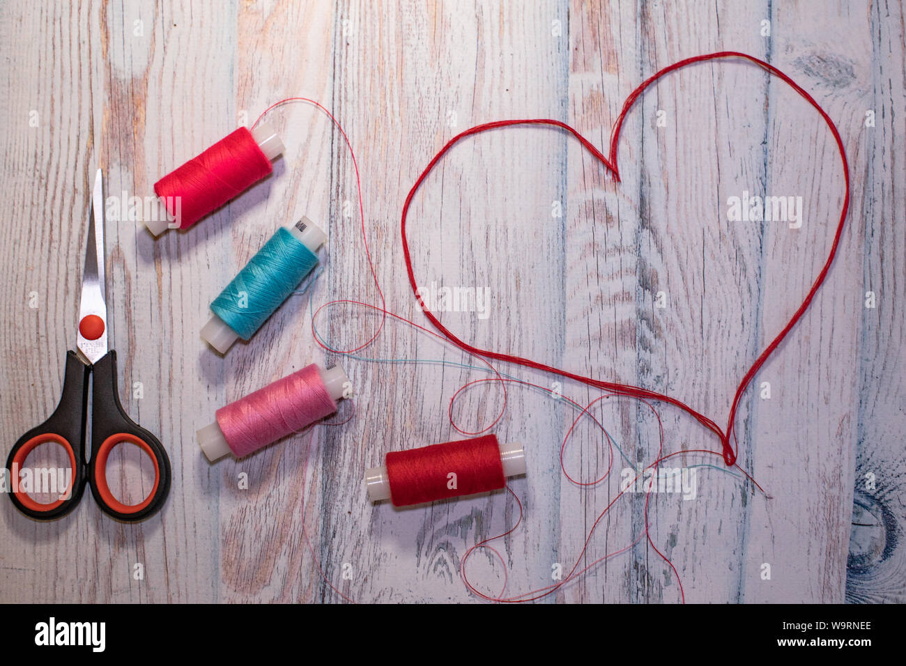 Hobbies and crafts concept, heart of factory threads on blue background ...