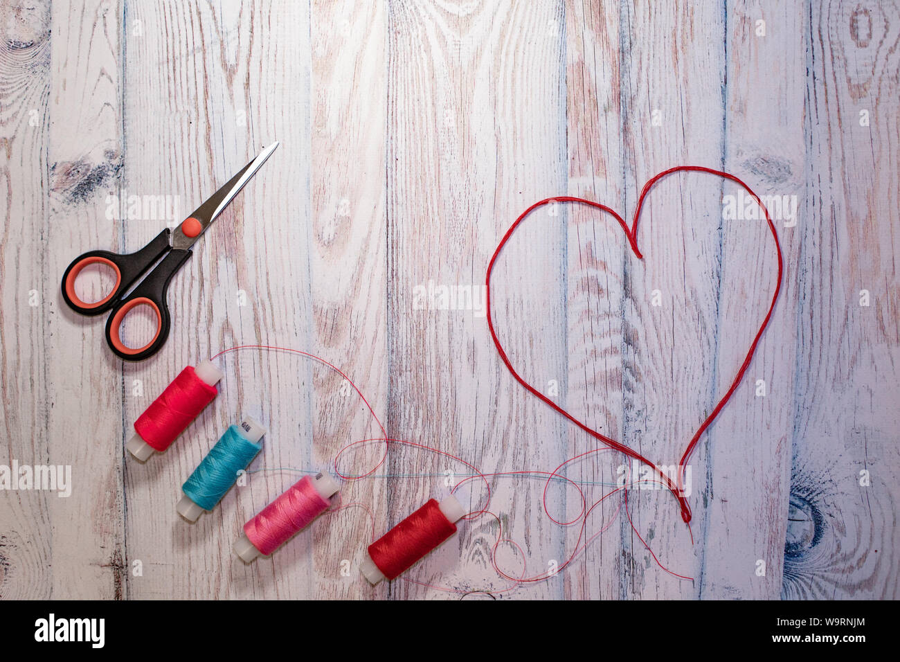 Hobbies and crafts concept, heart of factory threads on blue background ...