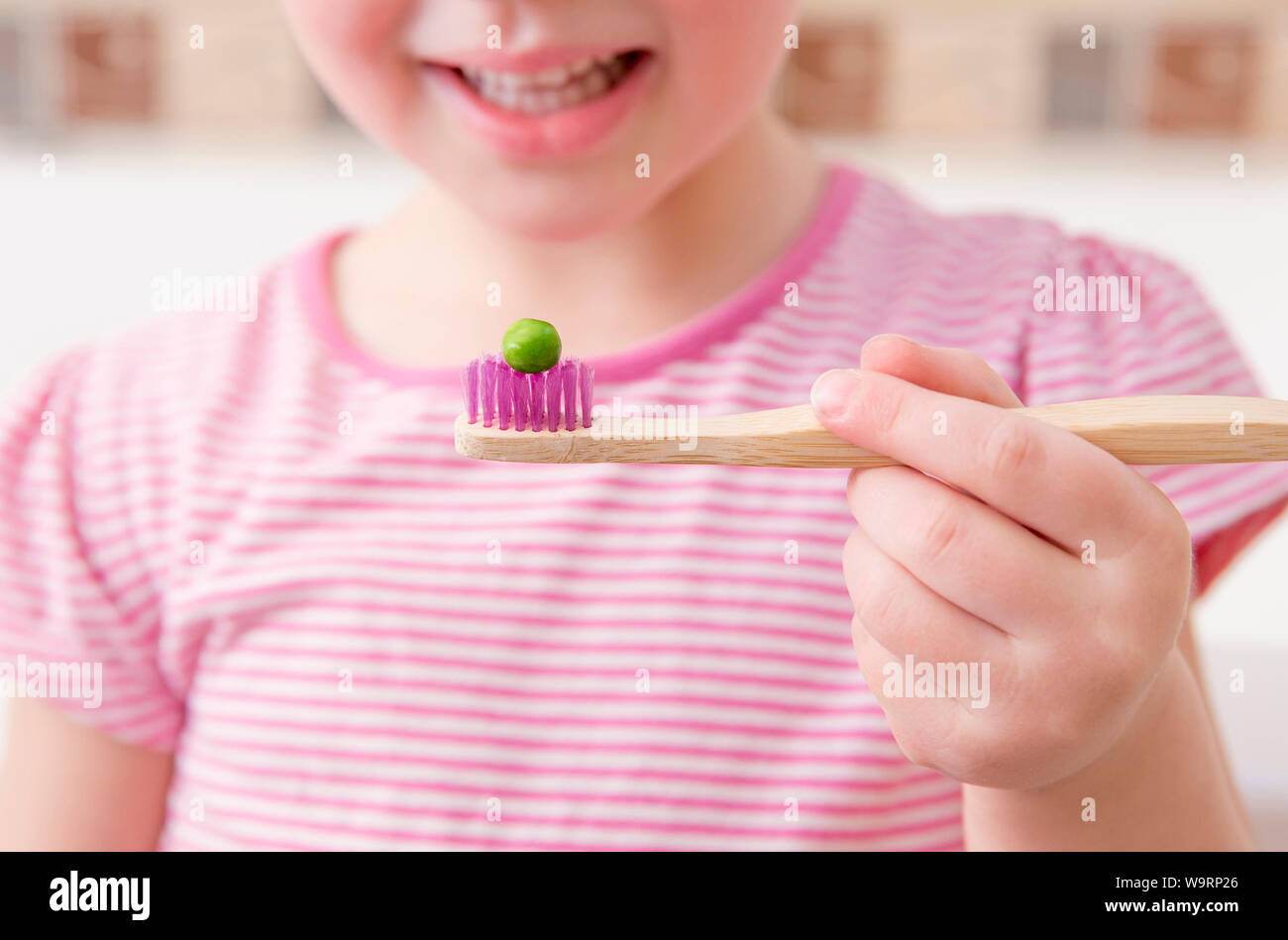 Selective focus on bamboo tooth brush with green pea on it and smiling ...