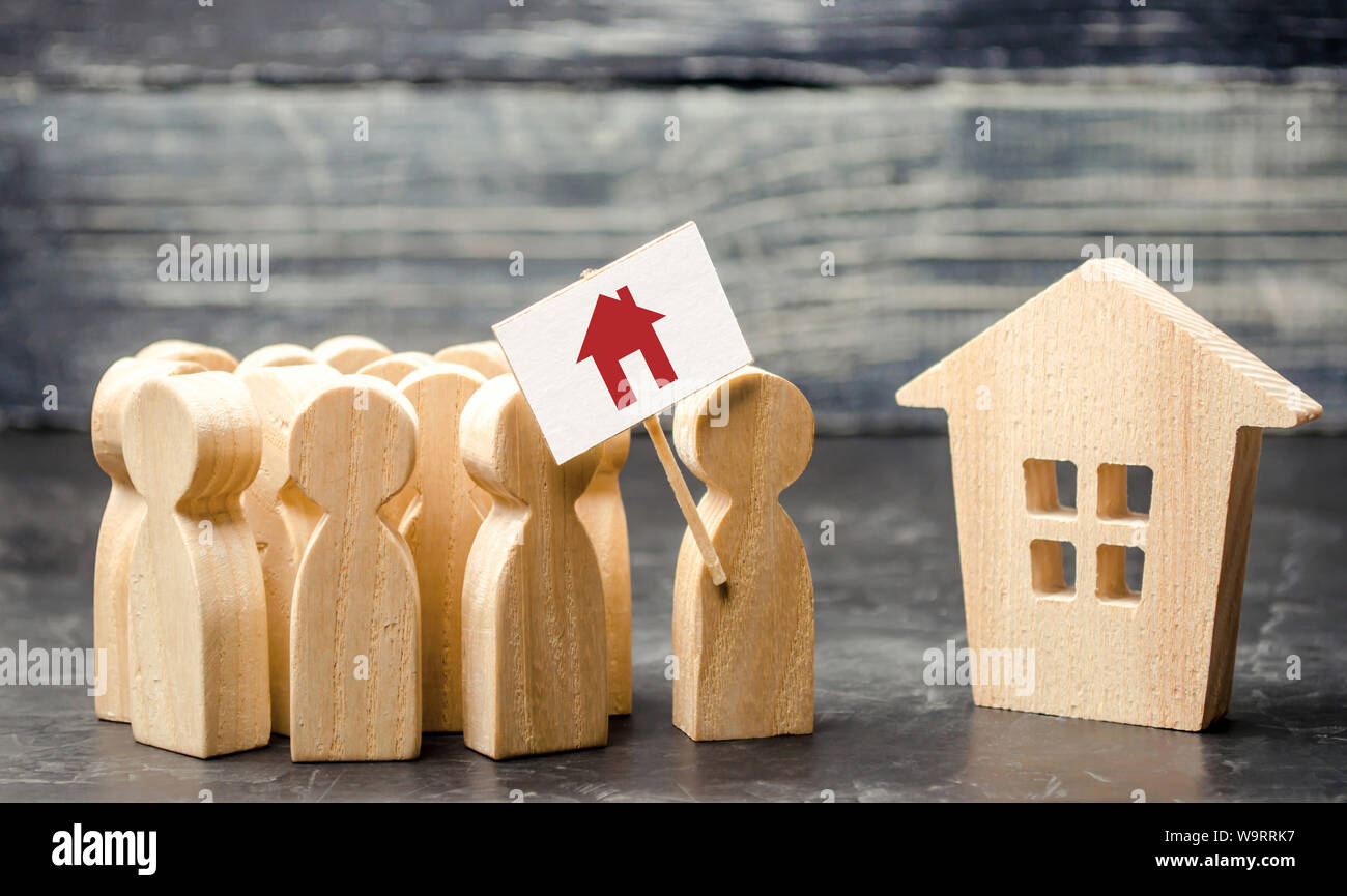 A crowd of people with a poster standing near the house. Residents of ...