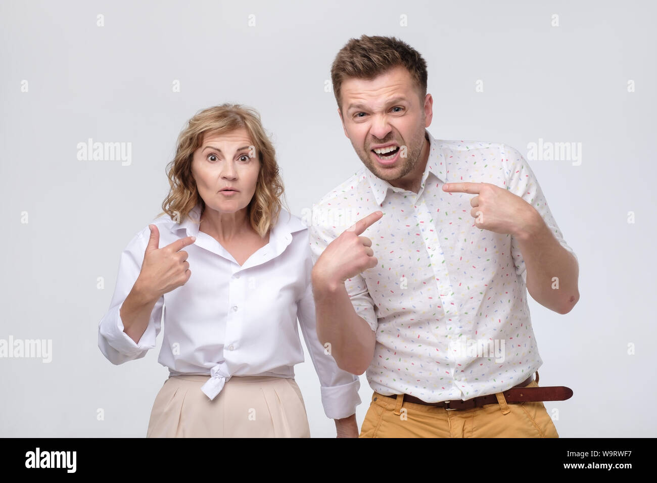 woman and man asking who me, being upset questioning pointing fingers ...