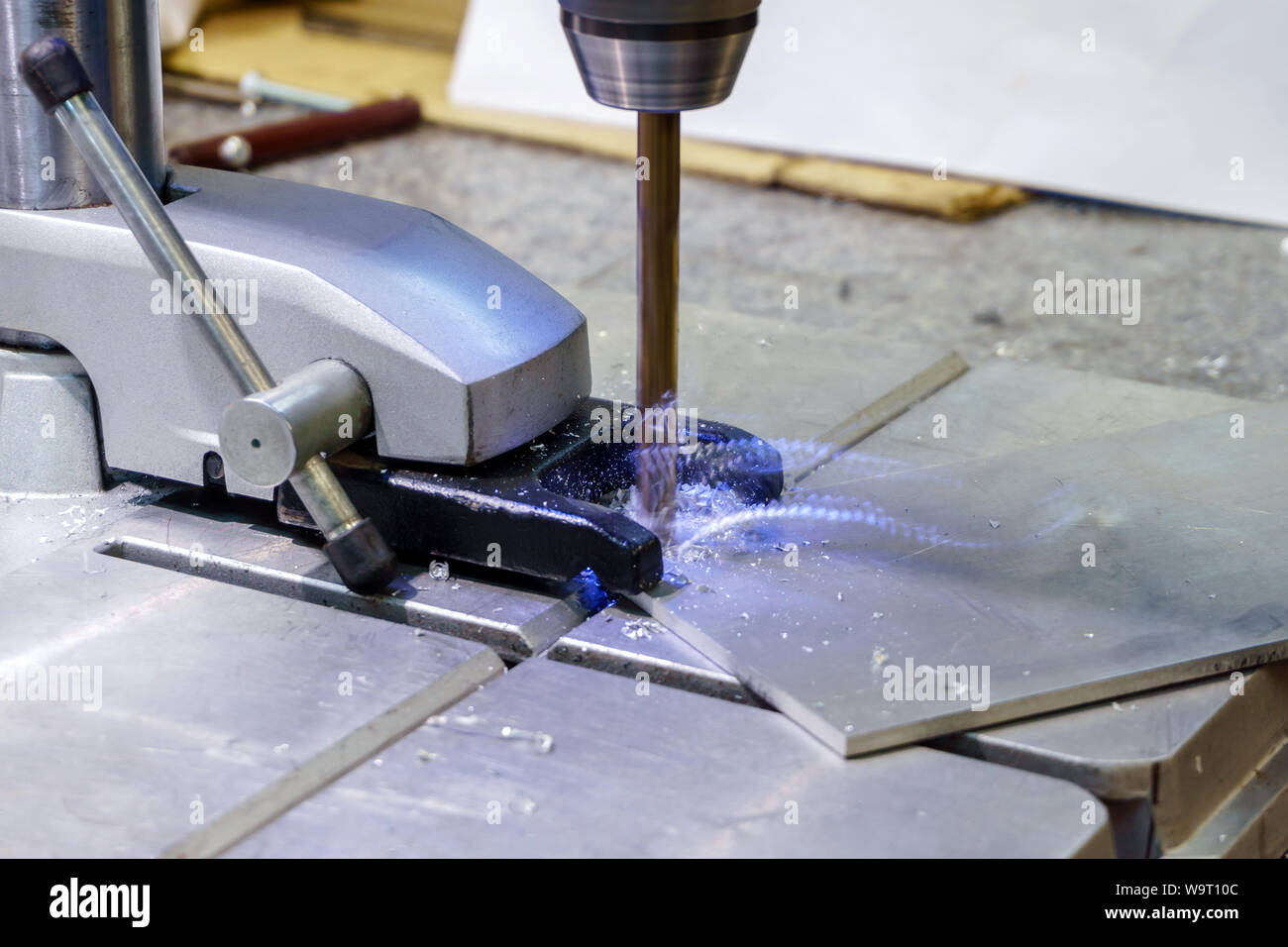 drilling process on small drill press close-up on a blurred workshop ...