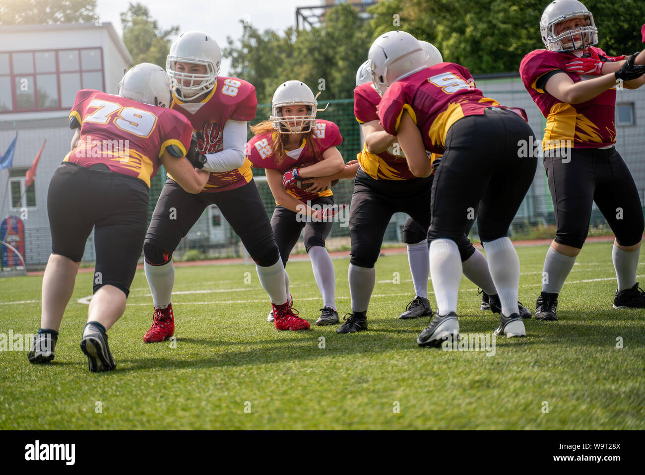 Full-length photo of athletes women playing american football on green ...
