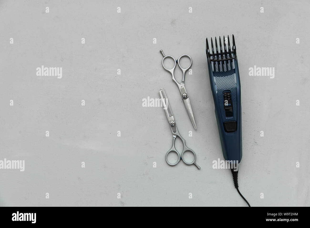 Hair trimmer and pair of stylish professional barber scissors on gray ...