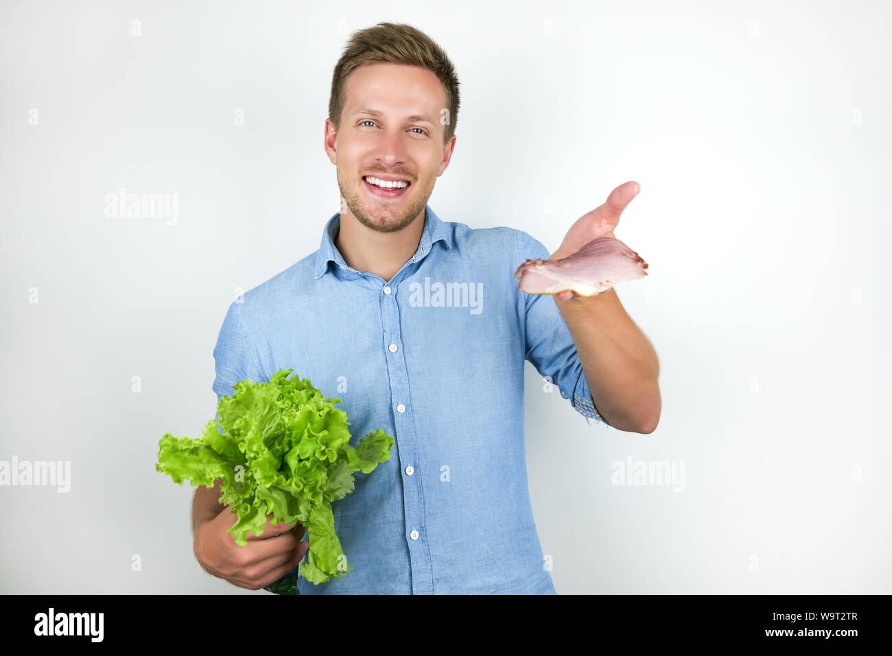 young handsome holding a whole bunch of salad and sliced bacon smiling ...