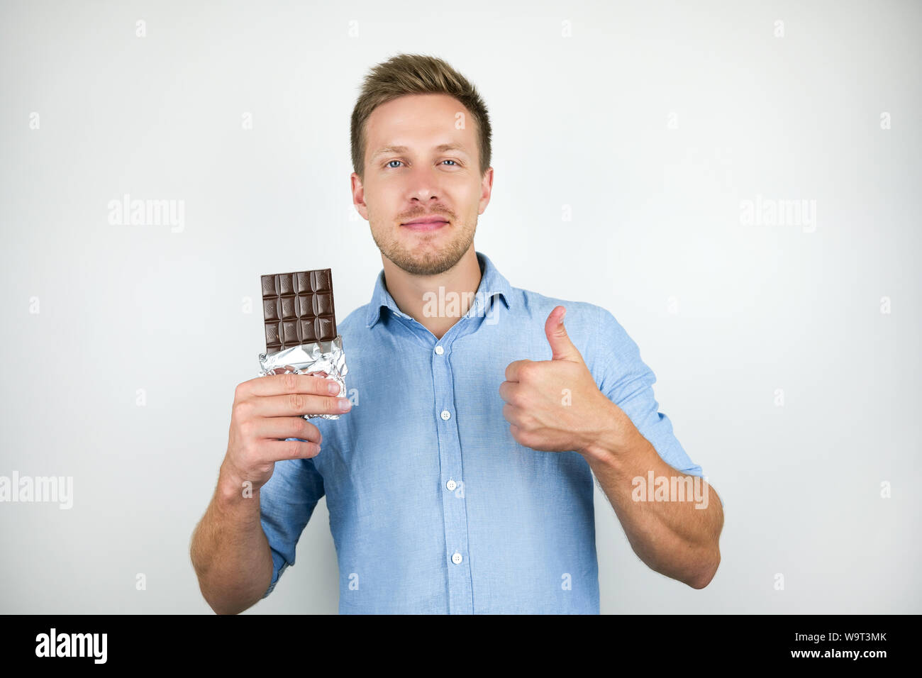 young handsome man holding chocolate bar showing like sign on isolated ...