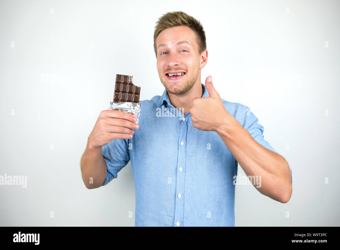 young handsome man holding chocolate bar showing like sign feeling ...
