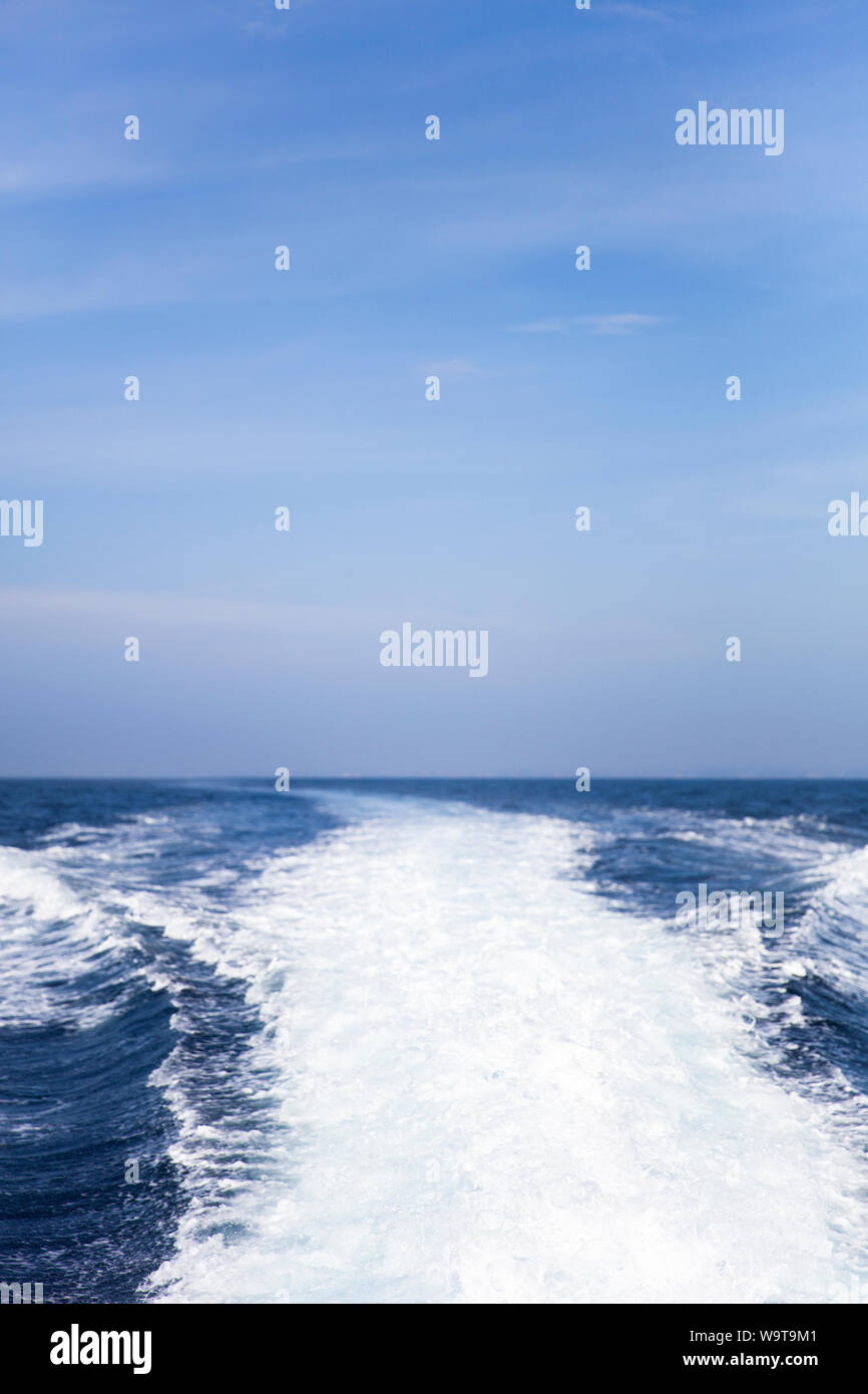 Water splash behind the speed boat in the ocean with beautiful blue sky ...