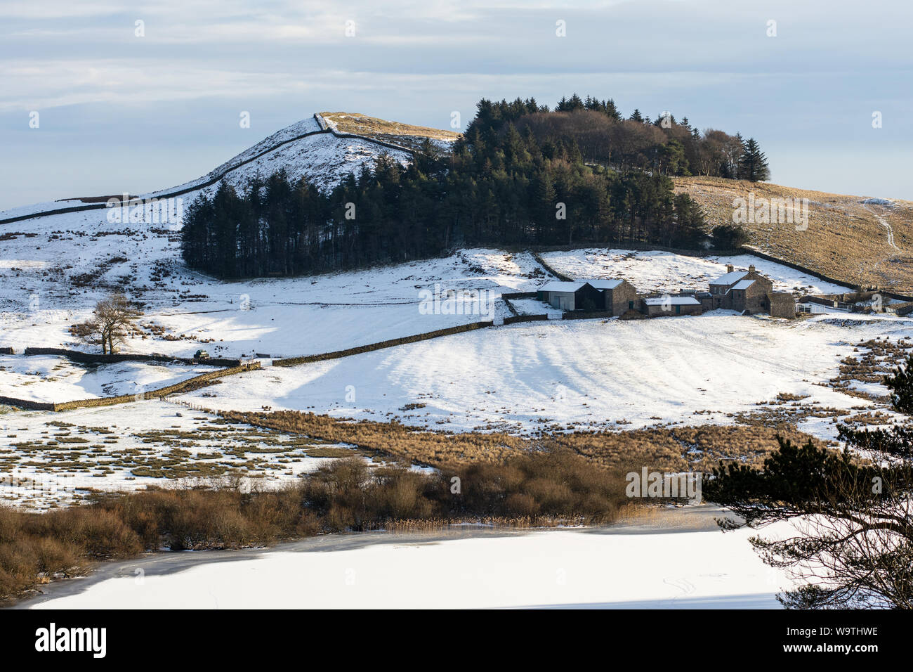 Winter snow lies on the fields of Hotbank farm beside the frozen lake ...