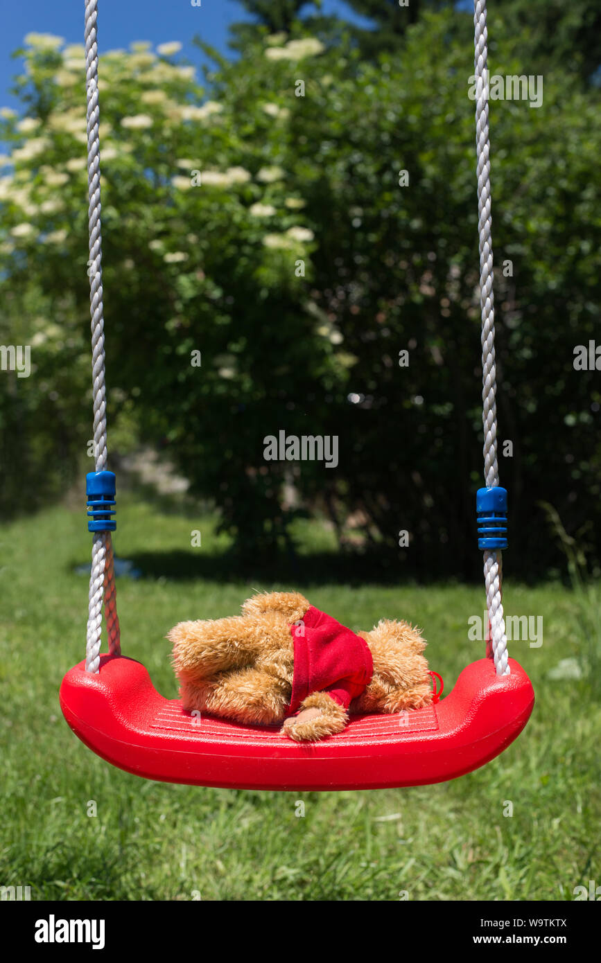 Teddy bear lying on a swing Stock Photo - Alamy