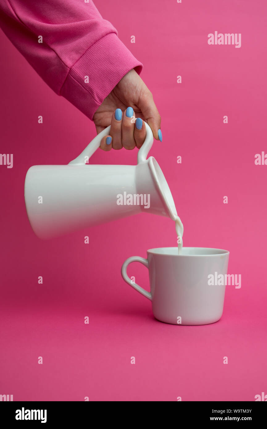Woman pouring a jug of milk into a mug Stock Photo - Alamy