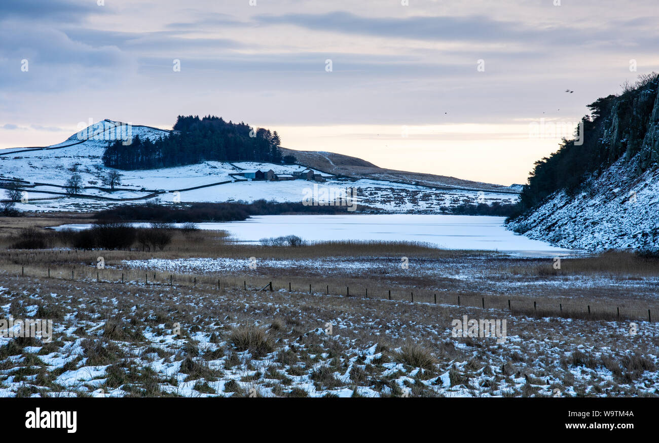 Winter snow lies on the fields of Hotbank farm beside the frozen lake ...