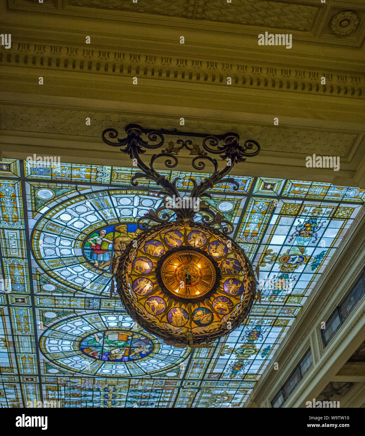 Beautiful classic glass clock with zodiac signs against a glass ceiling ...