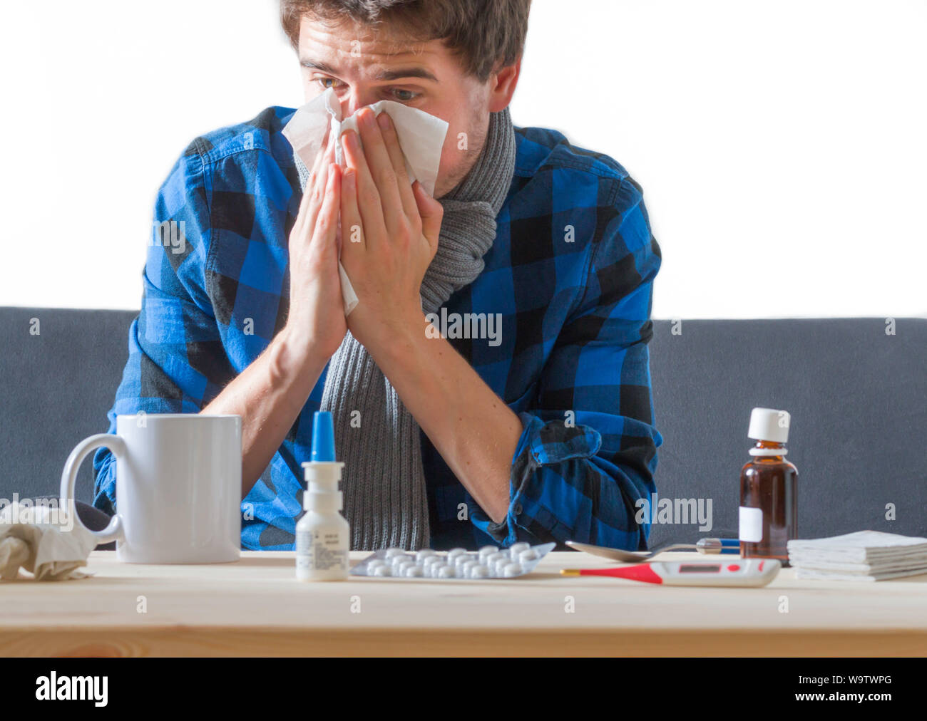 Young caucasian man in blue shirt is having a cold, sneezing in a ...