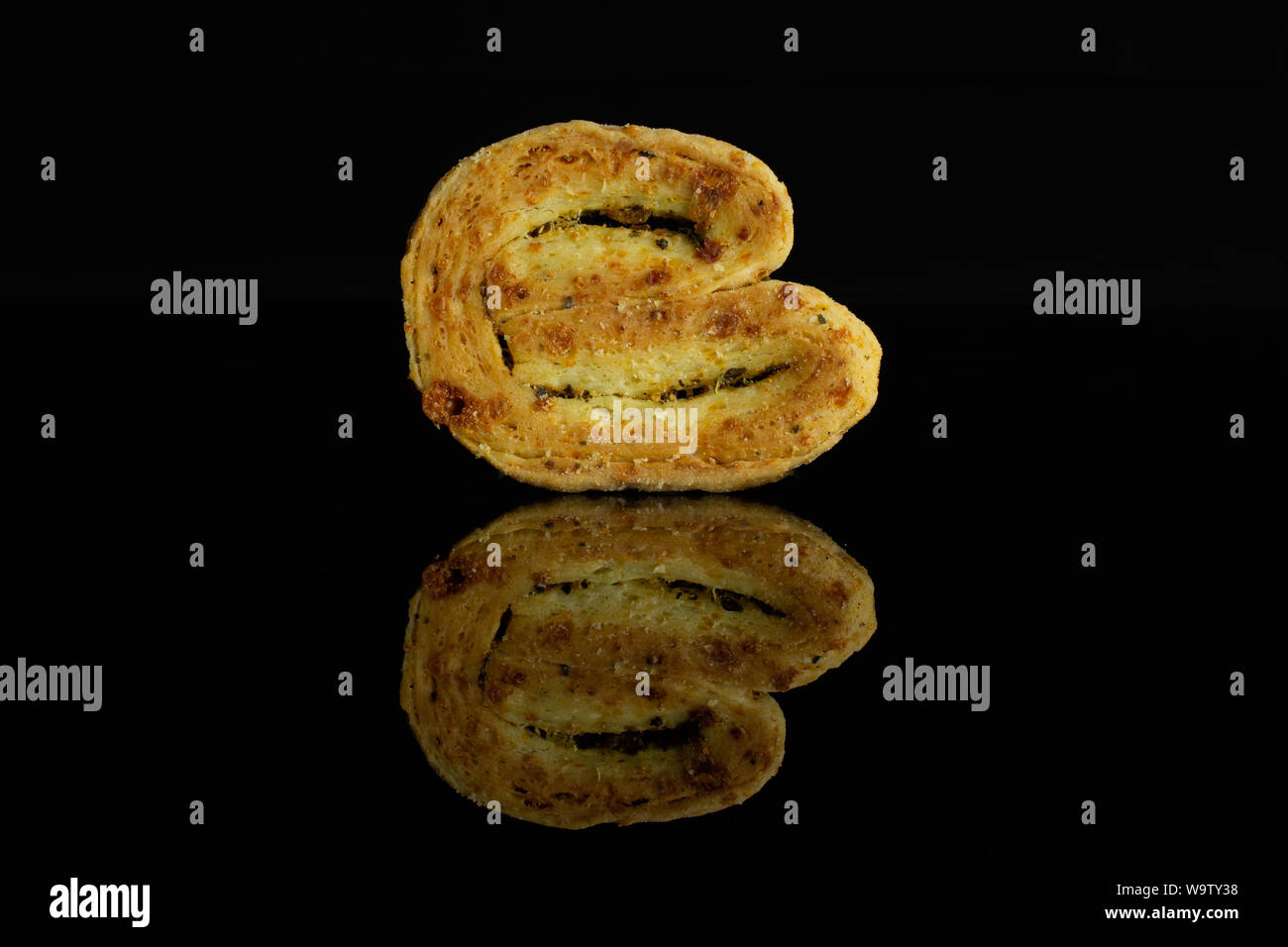 One whole savory cheese palmier isolated on black glass Stock Photo - Alamy