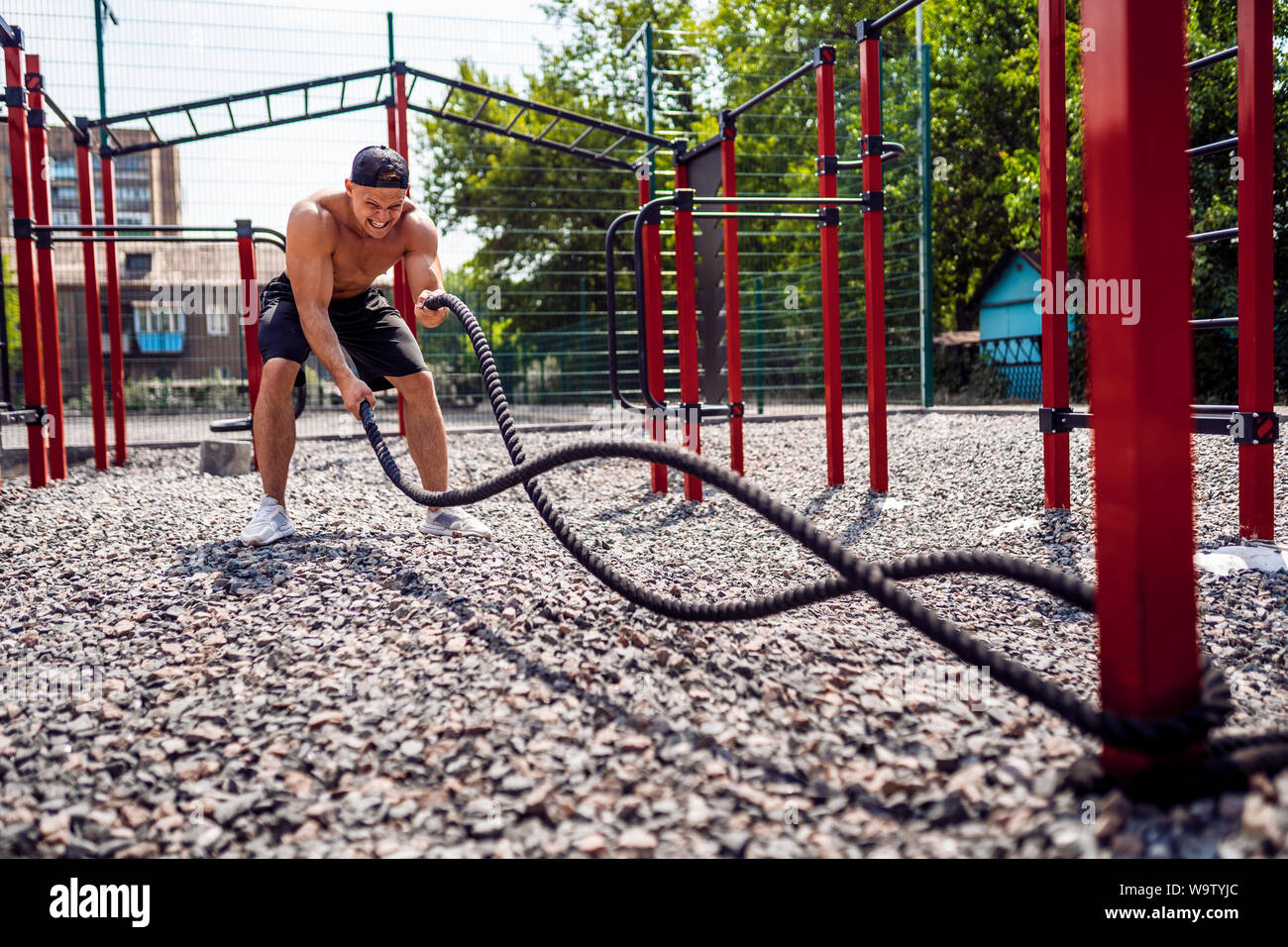 Athletic looking man working out with rope at street gym yard. Strength ...