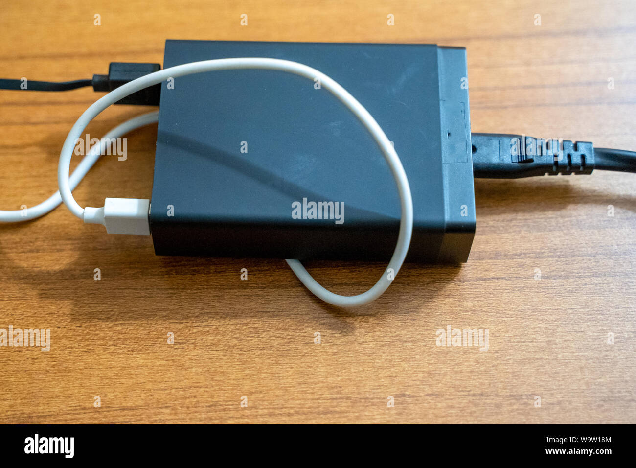 A multi hub USB power bank sitting on a wood table with two devices ...