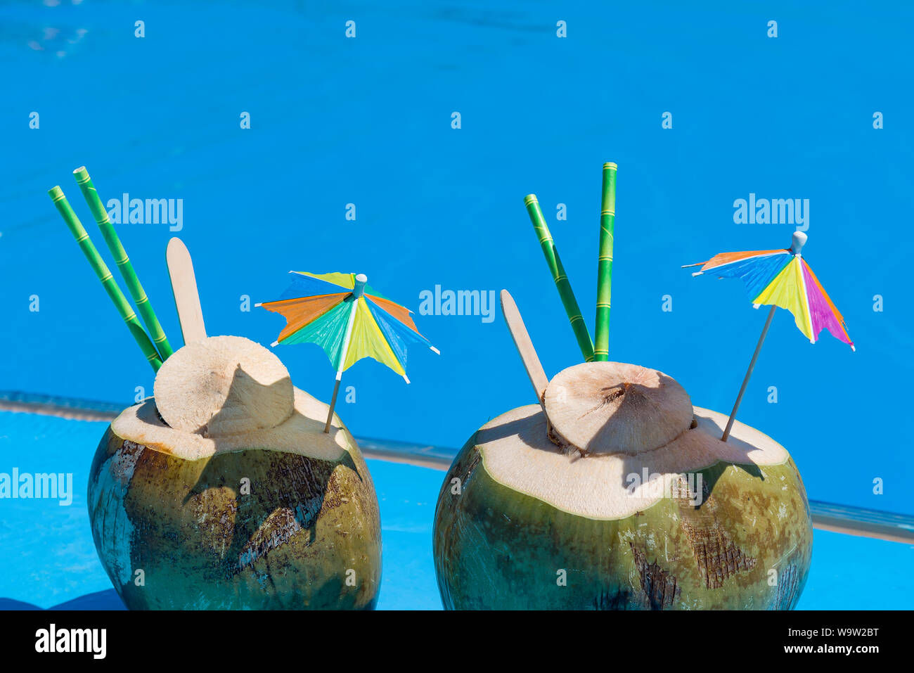 Fresh coconut cocktail Two coconuts on a blue background with umbrellas ...
