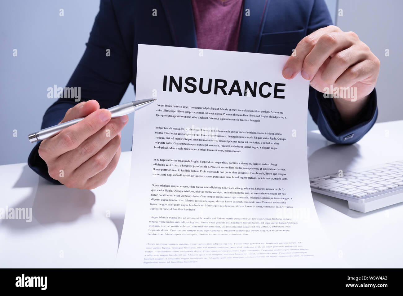 Mid Section Of A Businessman Showing Insurance Document Over White Desk ...
