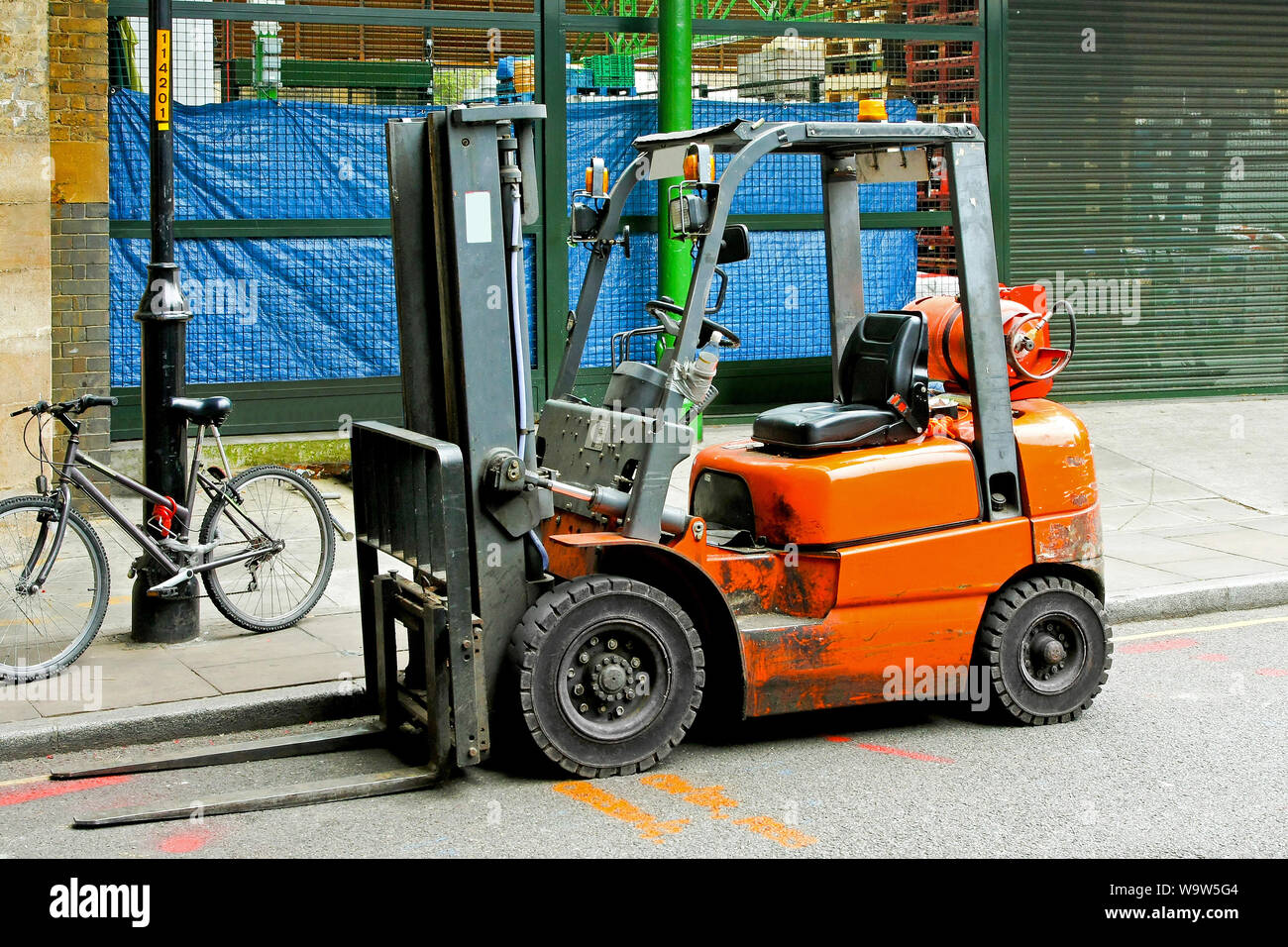 Orange forklift industrial vehicle at big warehouse Stock Photo - Alamy