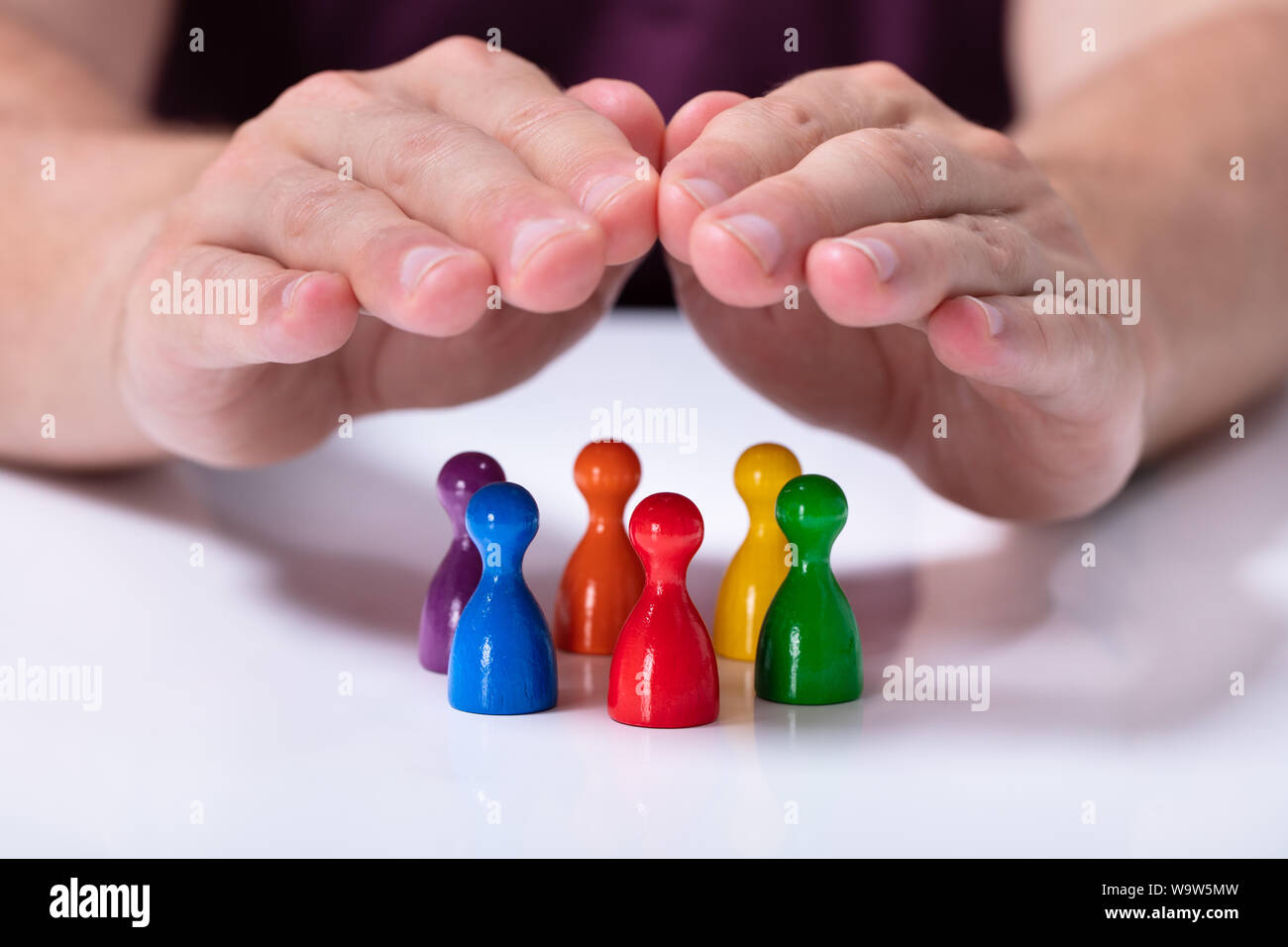 Close-up Of A Person's Hand Protecting Multicolored Pawns Forming ...