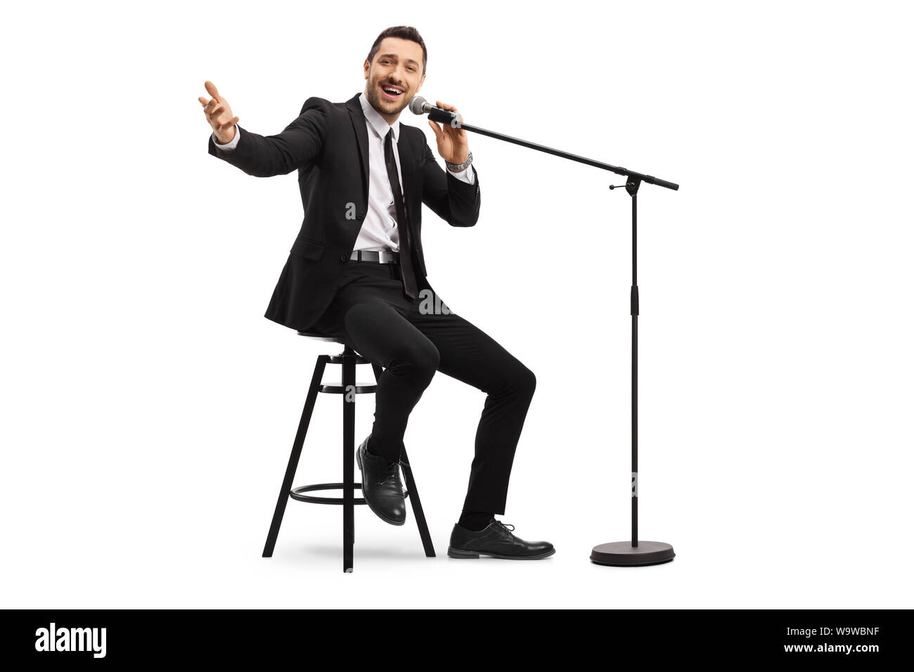 Full length shot of a male singer sitting on a chair and holding a ...