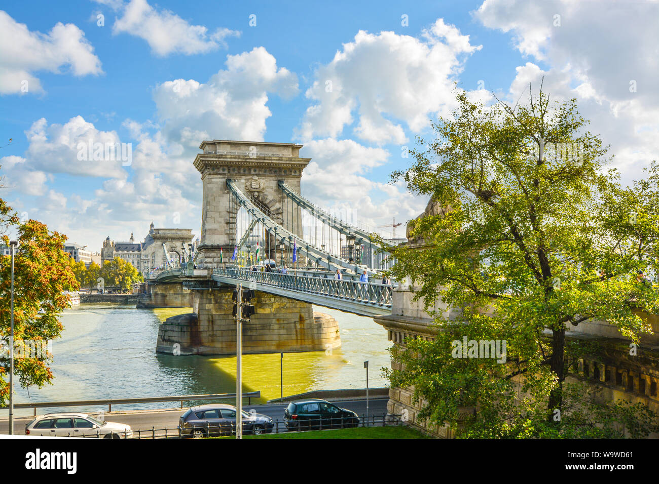 Tourists, cars and pedestrians cross the Chain Bridge near the stone ...