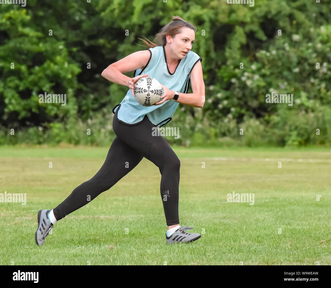 Female player running with the rugby ball in hand at amateur Touch ...