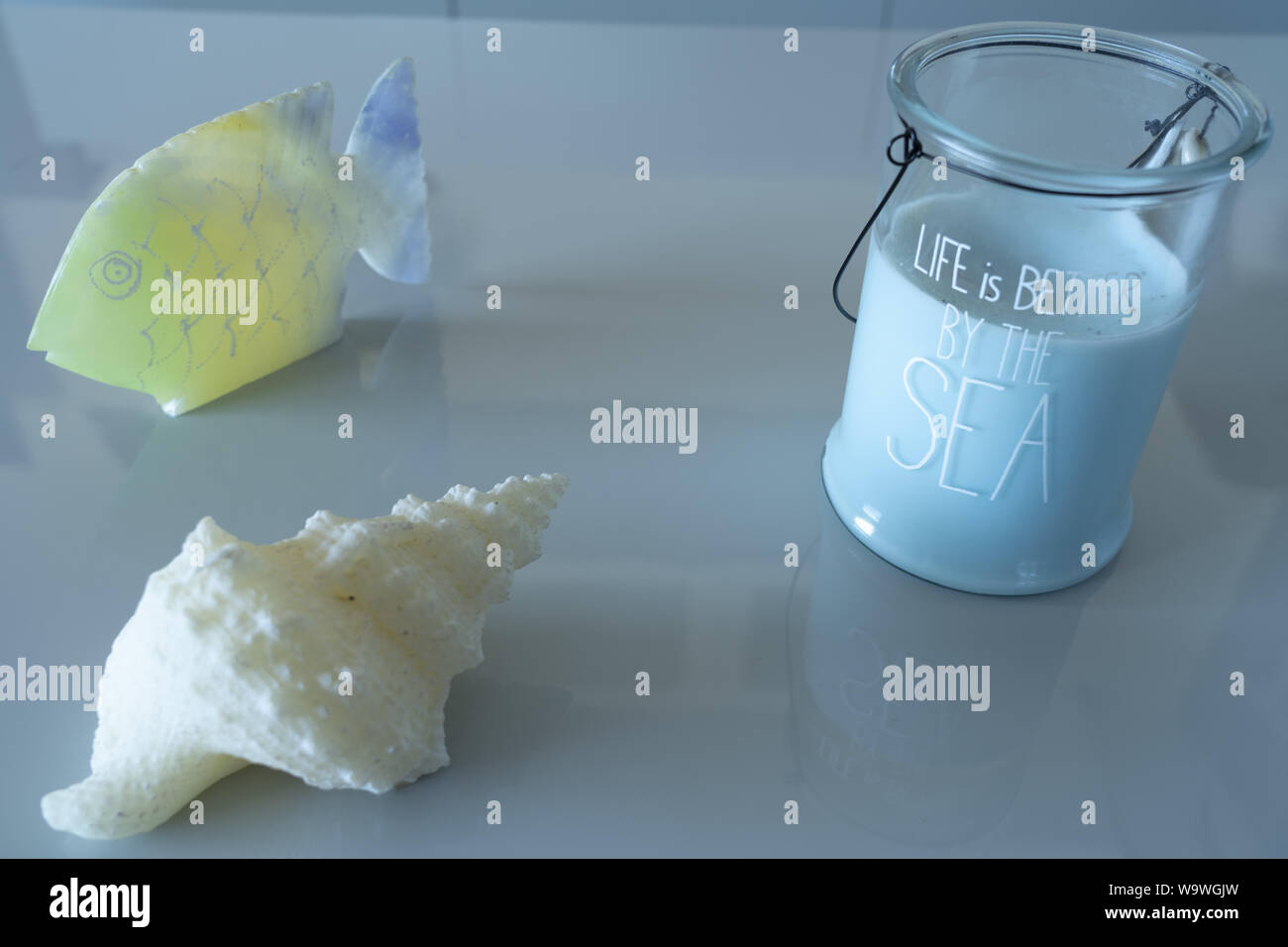 a shell and a glass fish with a candle in the mood that life is better ...