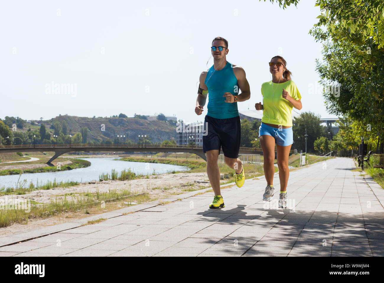 Two athletic people running through the riverside Stock Photo - Alamy