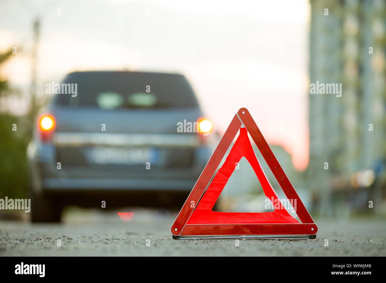 Red emergency triangle stop sign and broken car on a city street Stock ...