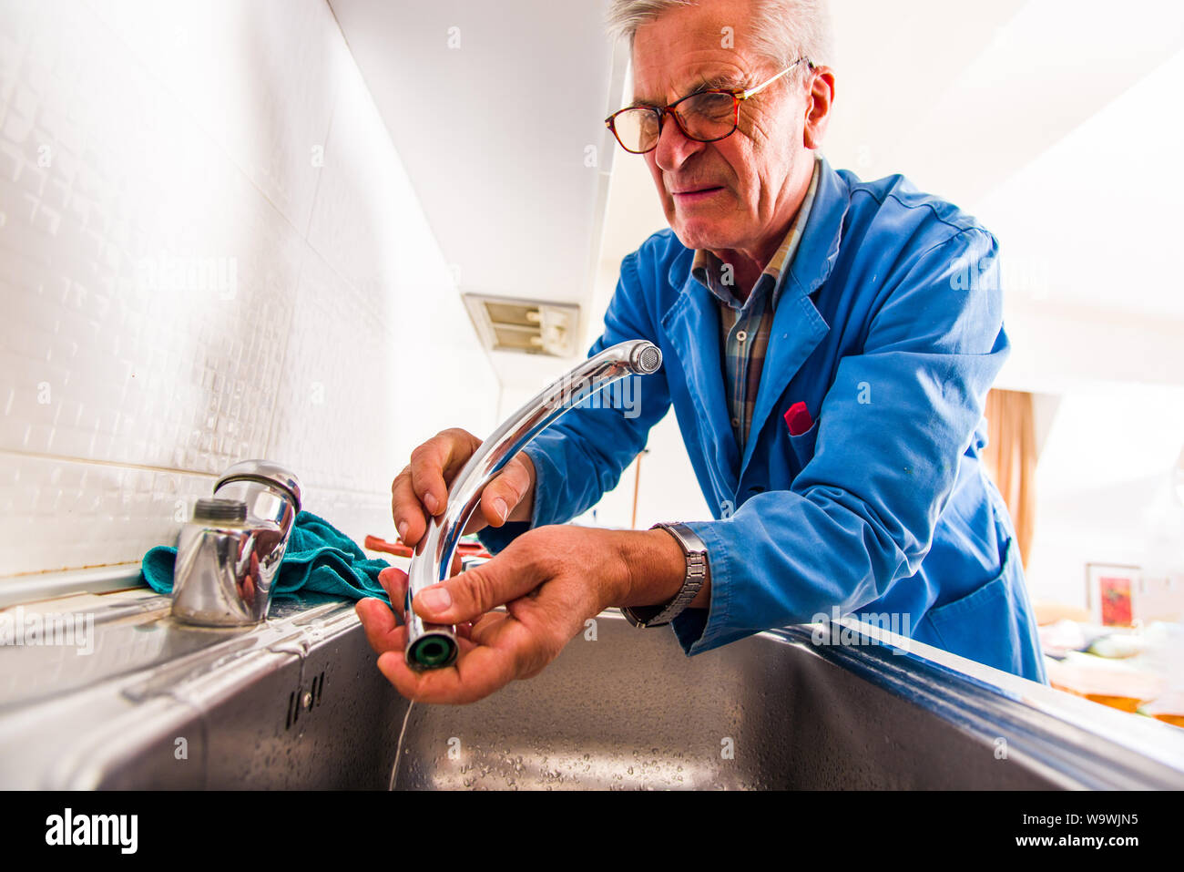 Mature handyman is fixing the broken kitchen faucet Stock Photo - Alamy