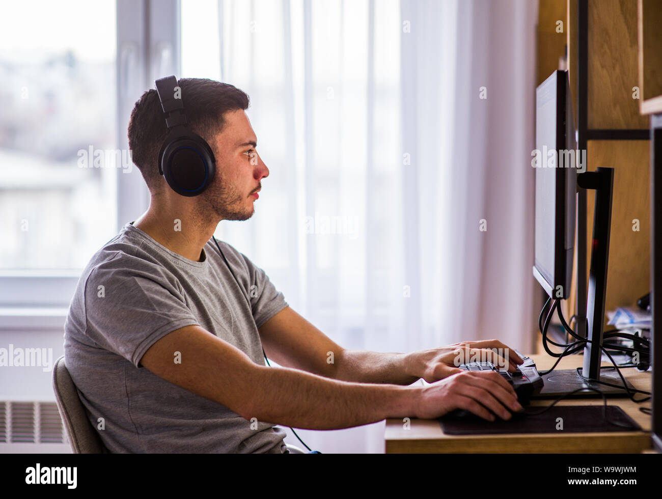 Serious man using desktop pc while typing on keyboard in his room Stock ...