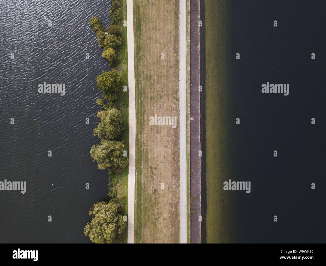 Aerial overhead shot of a brown road near the body of water at daytime ...