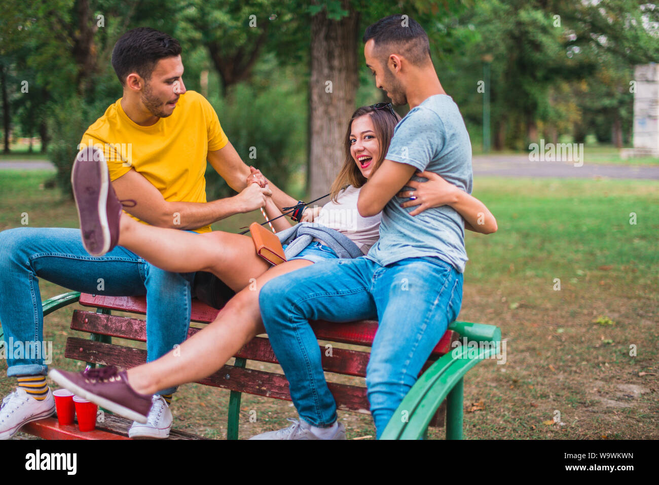 Friends are sitting on a bench in the park, making jokes and having fun ...