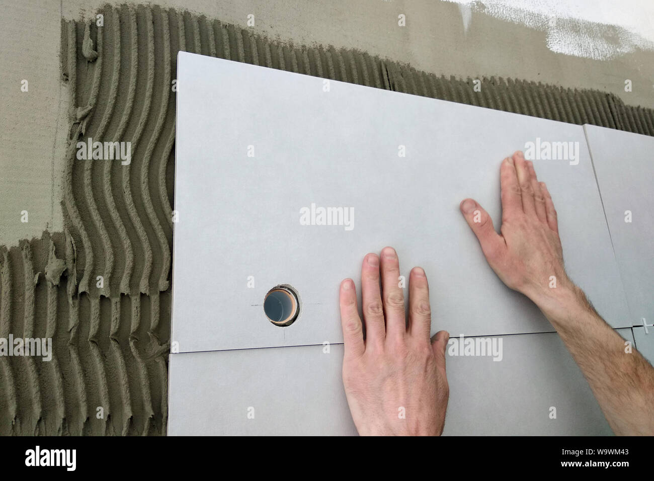 Worker hands putting ceramic tiles on the wall Stock Photo - Alamy