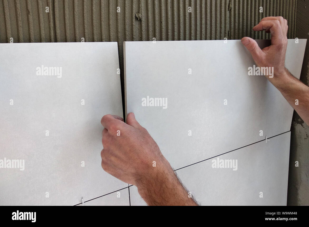 Worker hands putting ceramic tiles on the wall Stock Photo - Alamy