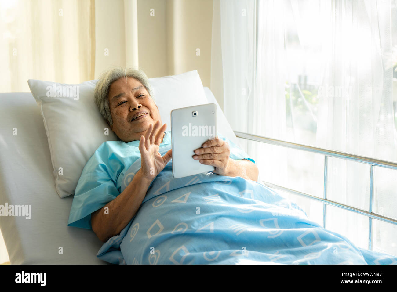 Asian senior using a digital touch screen tablet, she is connecting ...
