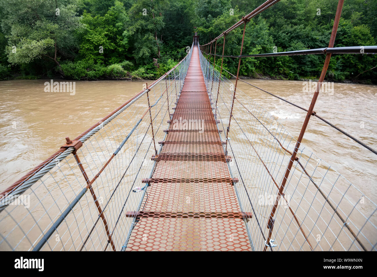 Narrow metal foot bridge across river in summer Stock Photo - Alamy