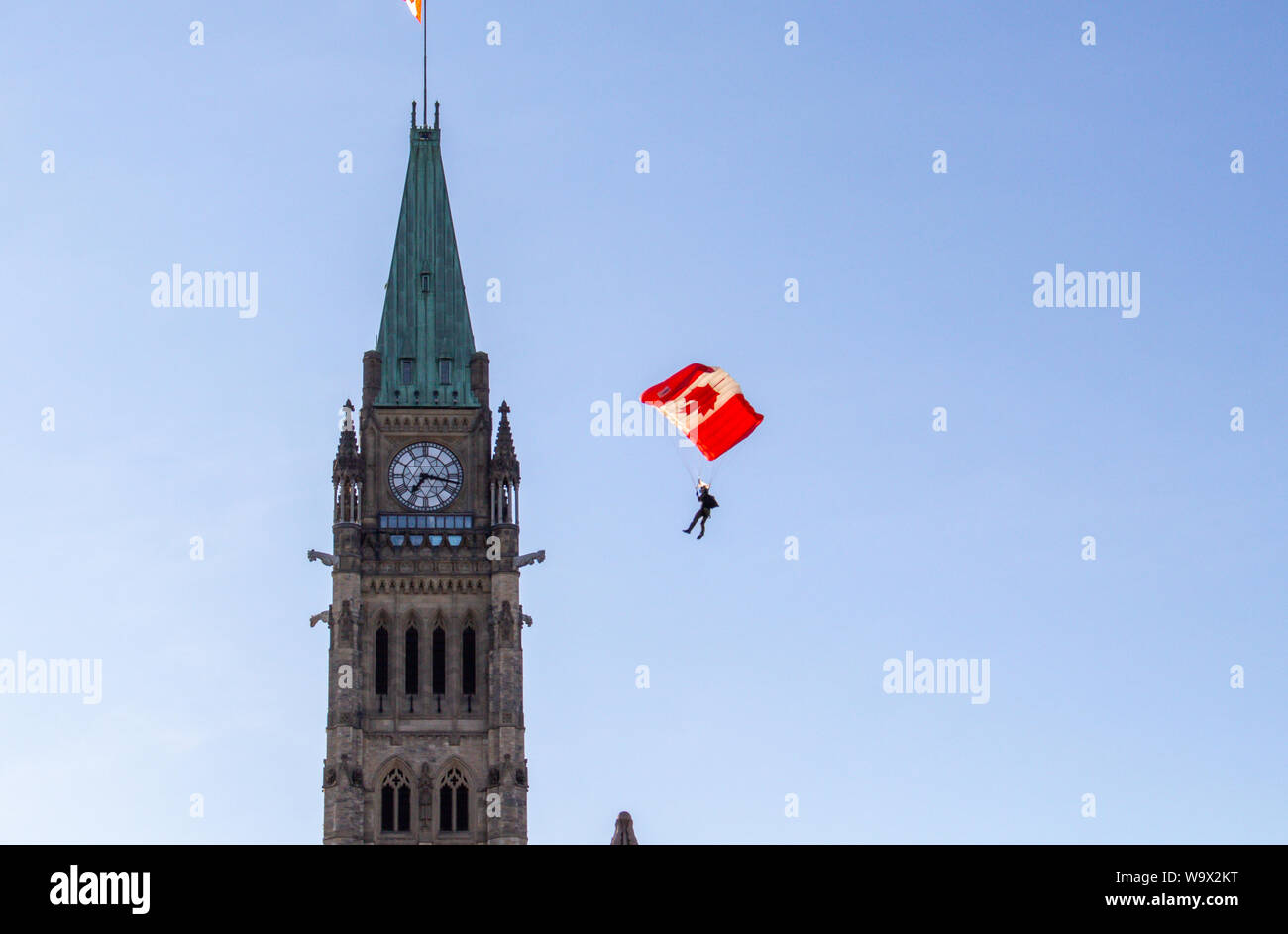 A parachute with the Canadian Flag's design descends by the Peace Tower ...